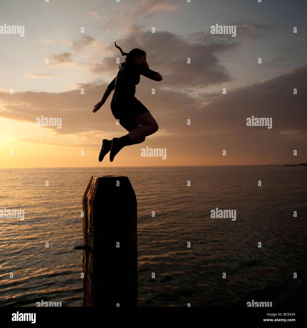 Teenage girl jumping into the sea on a summer evening wales UK Stock ...