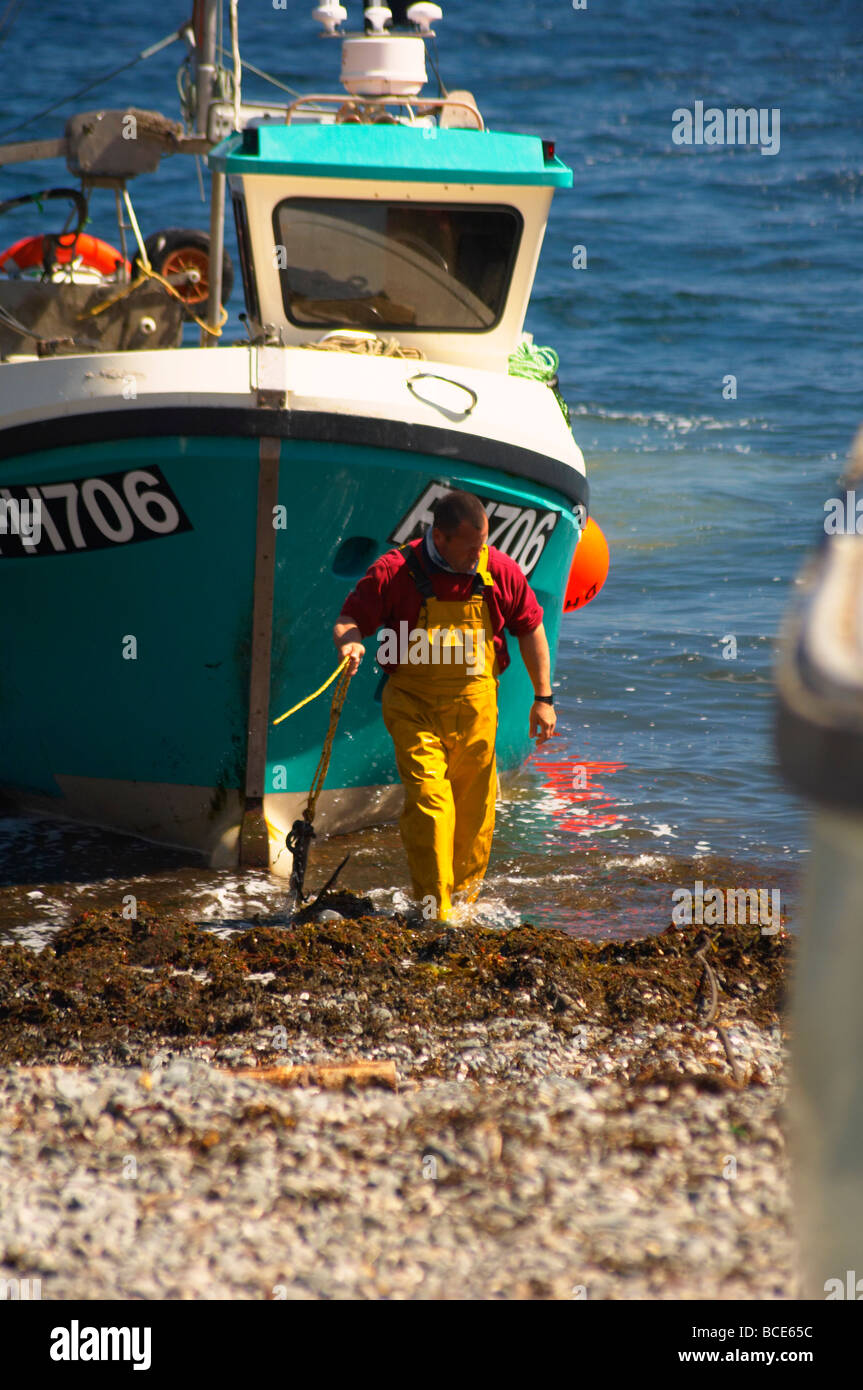 Fisherman landing his trawler on the beach after a mornings fishing at ...