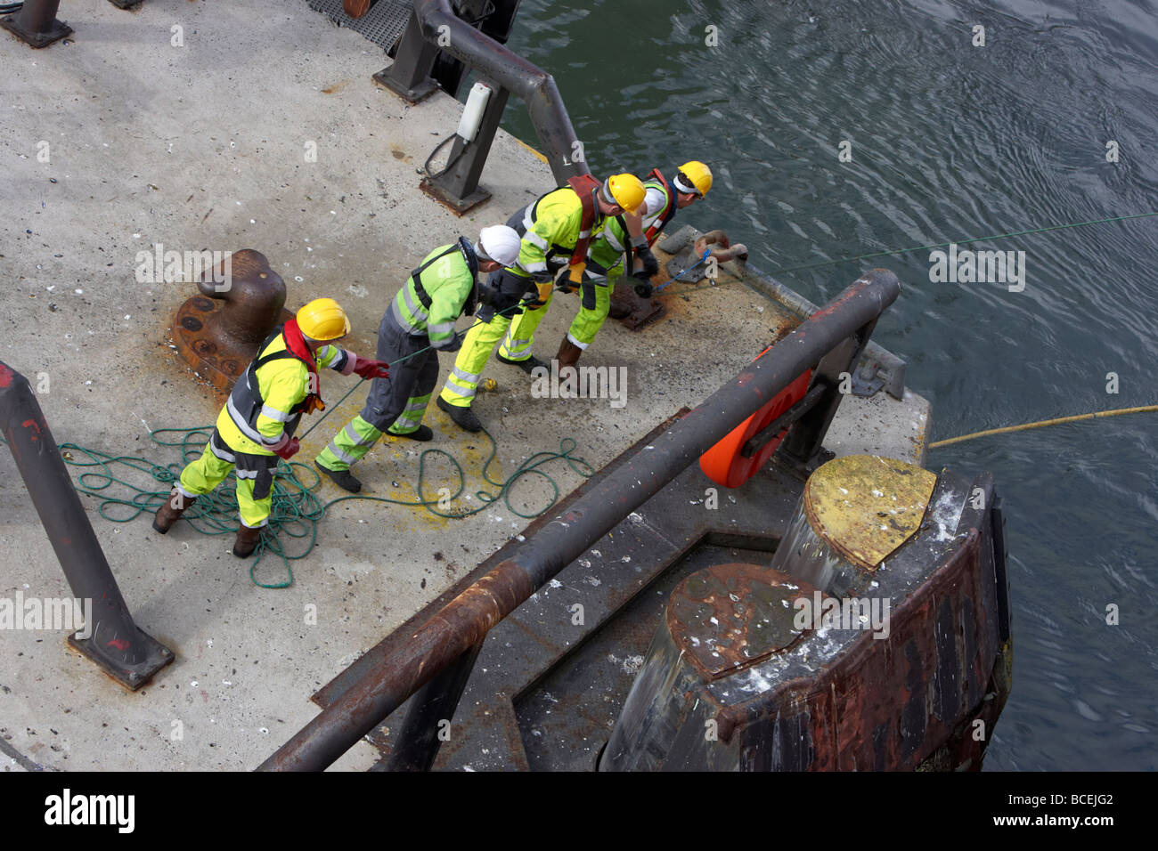 shore crew pull safety line connected to ship rope onto quay while ...