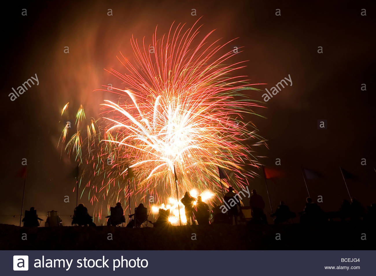 A group of people watch fireworks light up the sky at a fiesta Stock ...