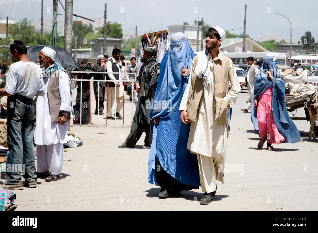 A young couple, the woman in the standard blue burqa, walking a busy ...