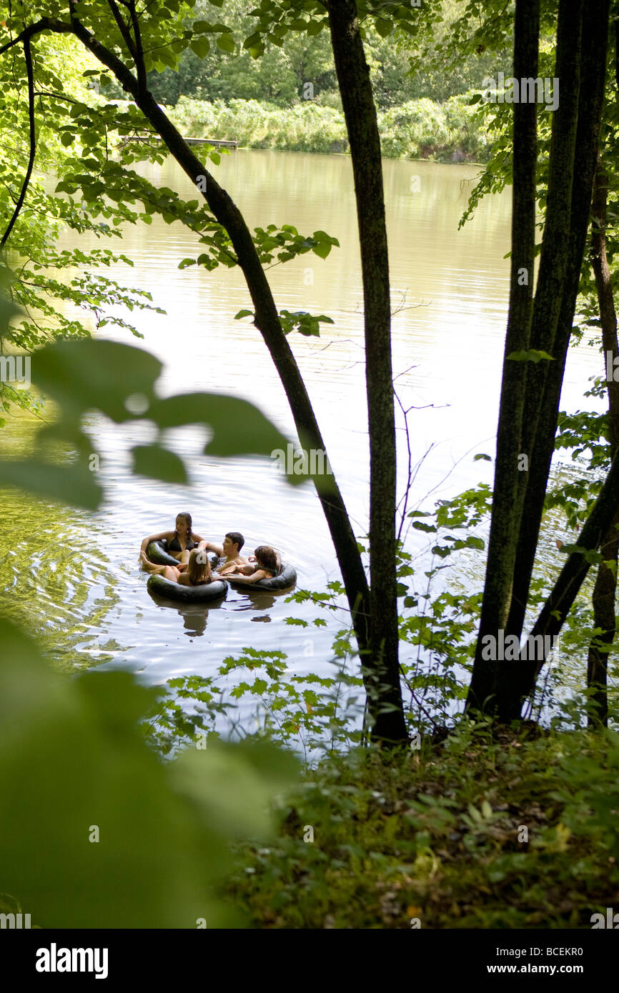 Teenagers floating on innertubes near a wooded area Stock Photo - Alamy
