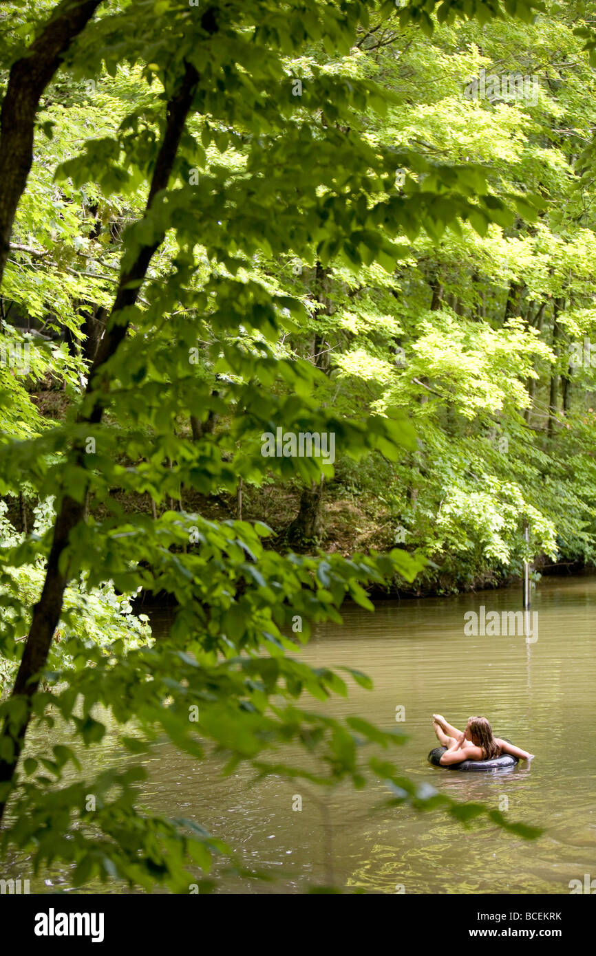 Teenage girl floats on an innertube near a wooded area Stock Photo - Alamy