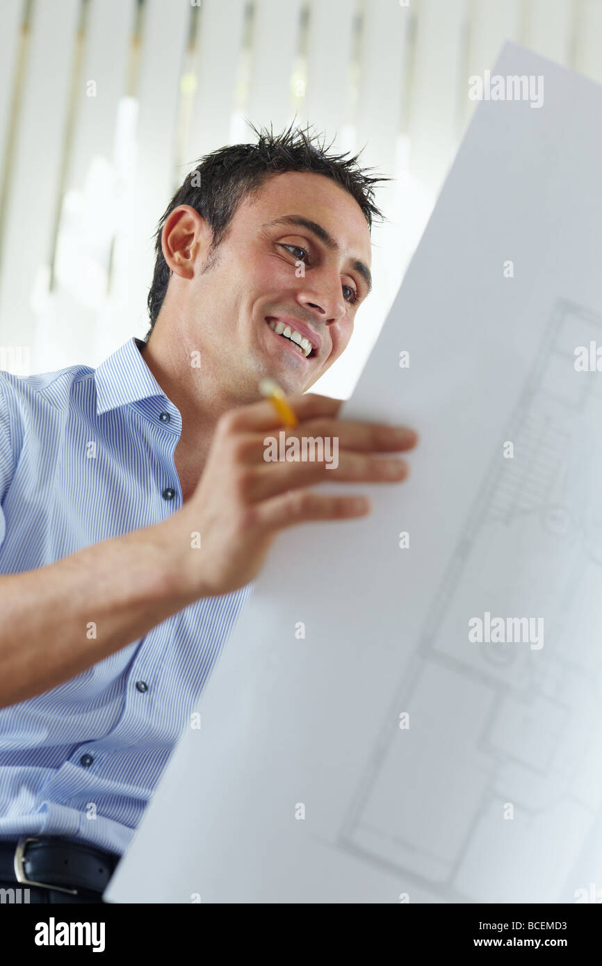 male architect looking at blueprint and smiling Stock Photo - Alamy