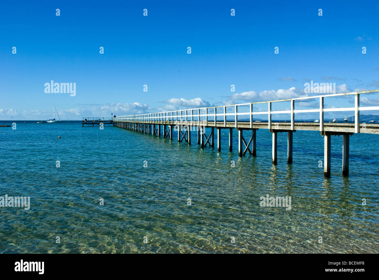 A small wooden jetty reaches into a bay on a clear winters day Stock ...