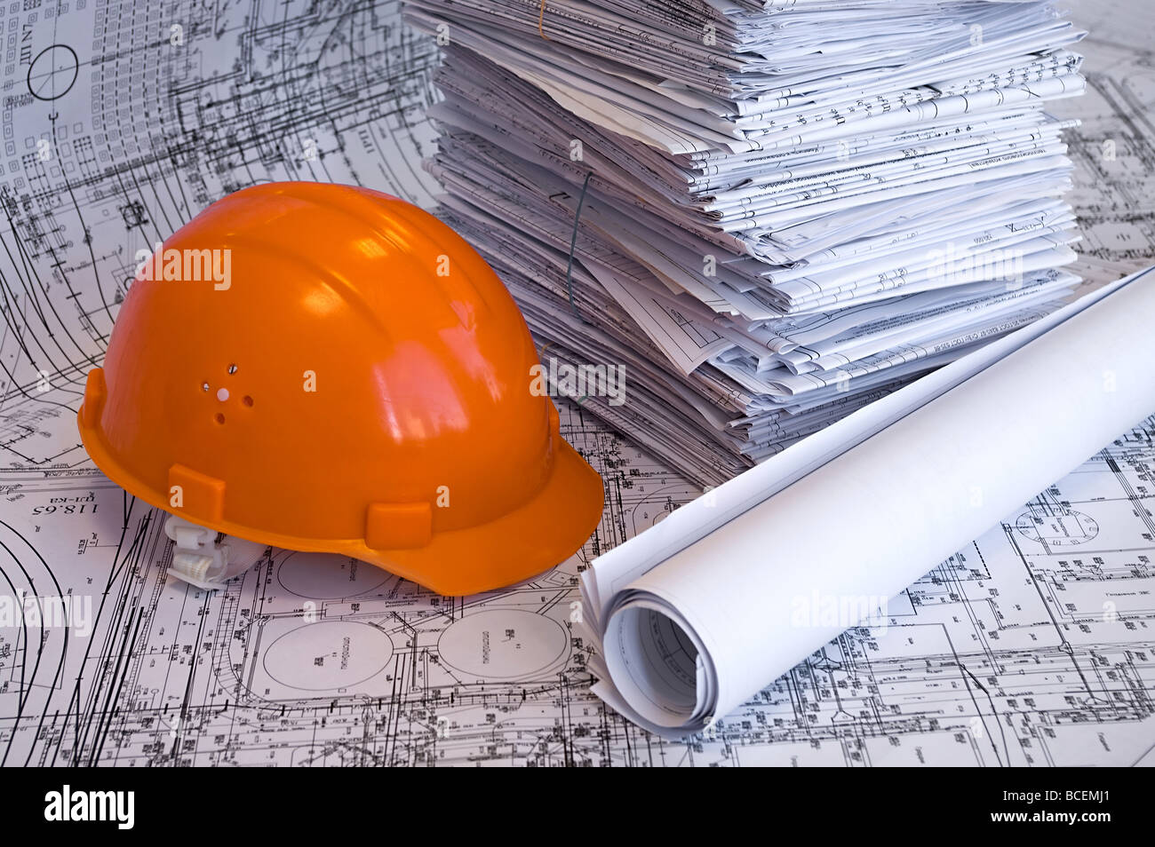 Yellow, red file folders, helmet and heap of design drawings are on the ...