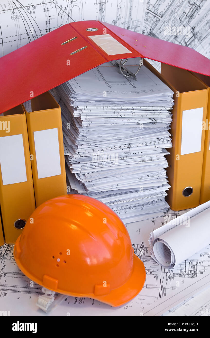 Yellow, red file folders, helmet and heap of design drawings are on the ...