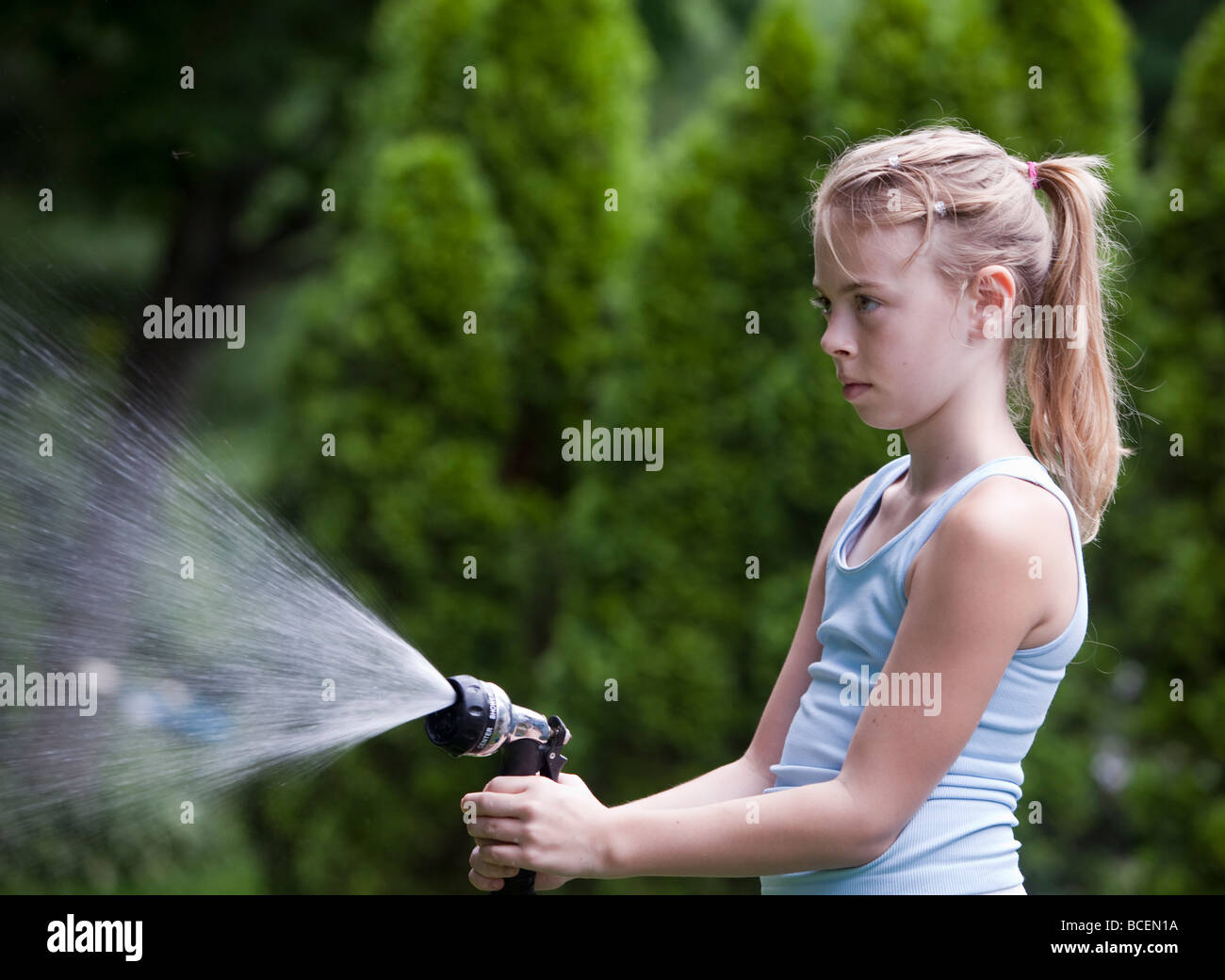 Young girl spraying water with a hose Stock Photo - Alamy
