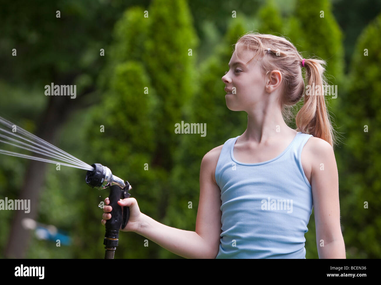 Young girl spraying water with a hose Stock Photo - Alamy