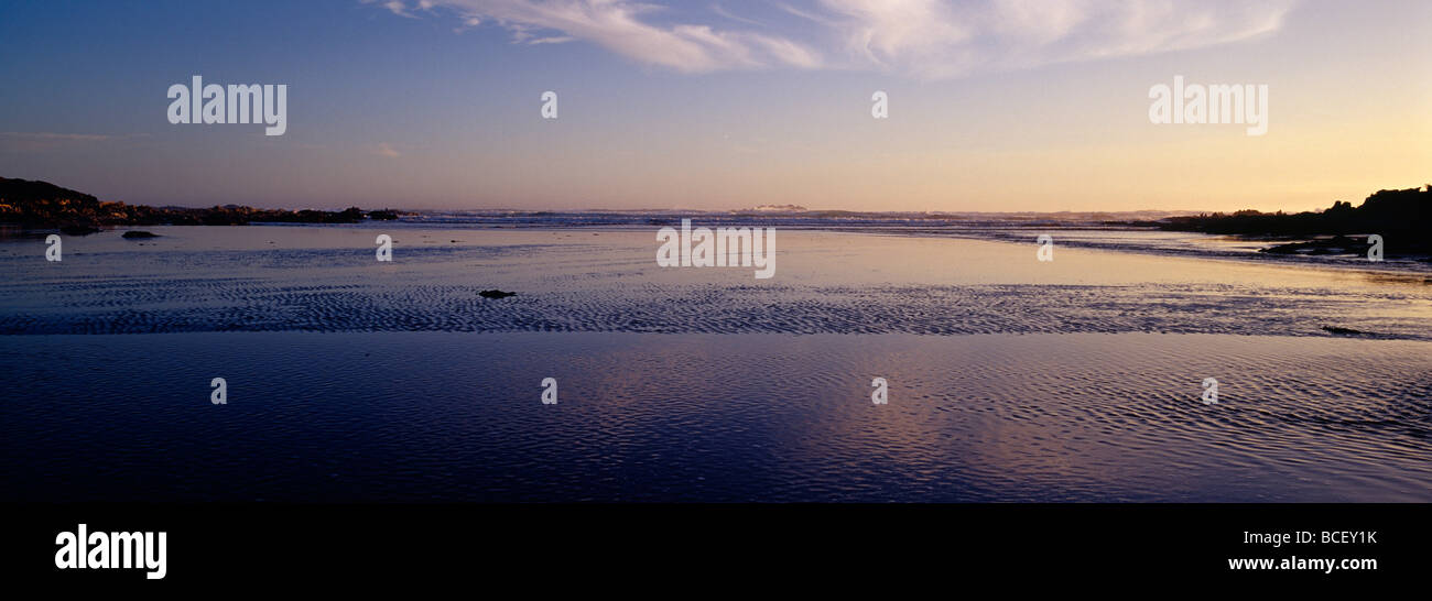 Sunset falls in pastel hues over the shallow waters of a tidal inlet ...