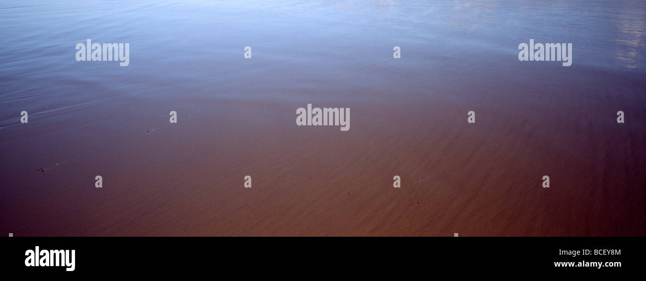 A clear blue sky reflected in a smooth wet beach at low tide Stock ...