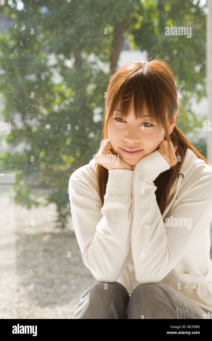 Young woman sitting near window Stock Photo - Alamy