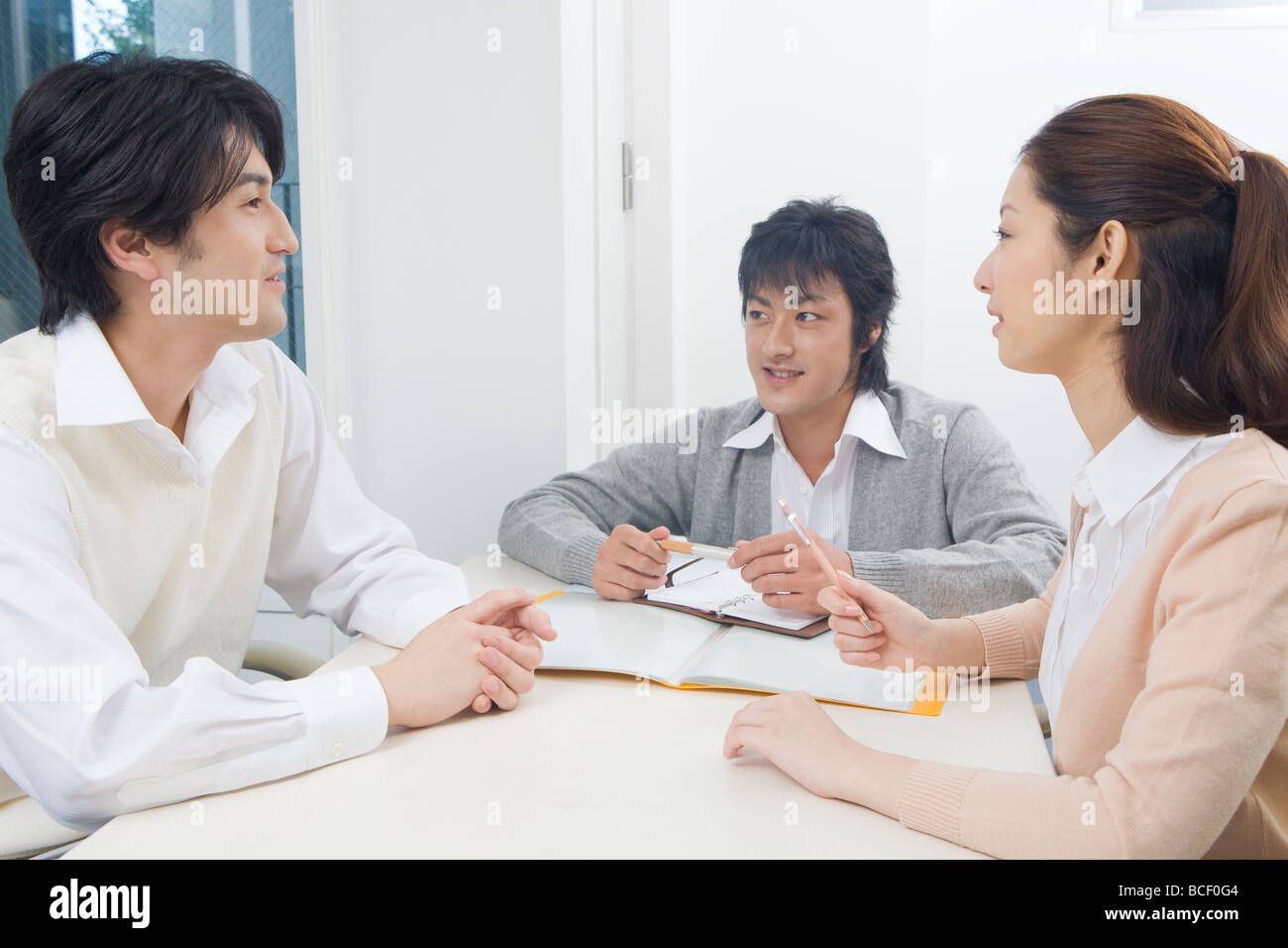 Three people discussing in office Stock Photo - Alamy
