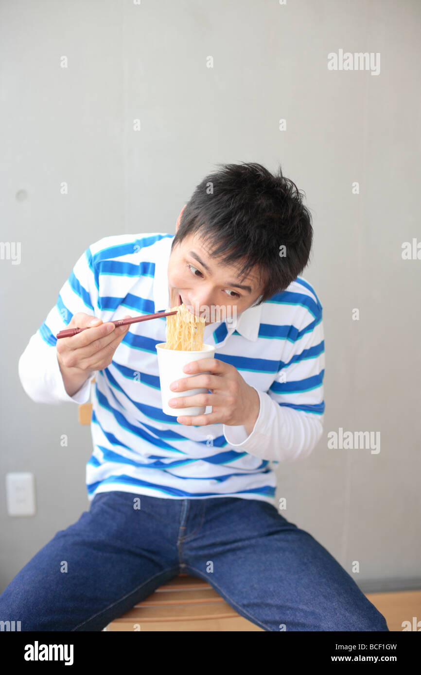 Mid adult man eating instant noodle Stock Photo - Alamy