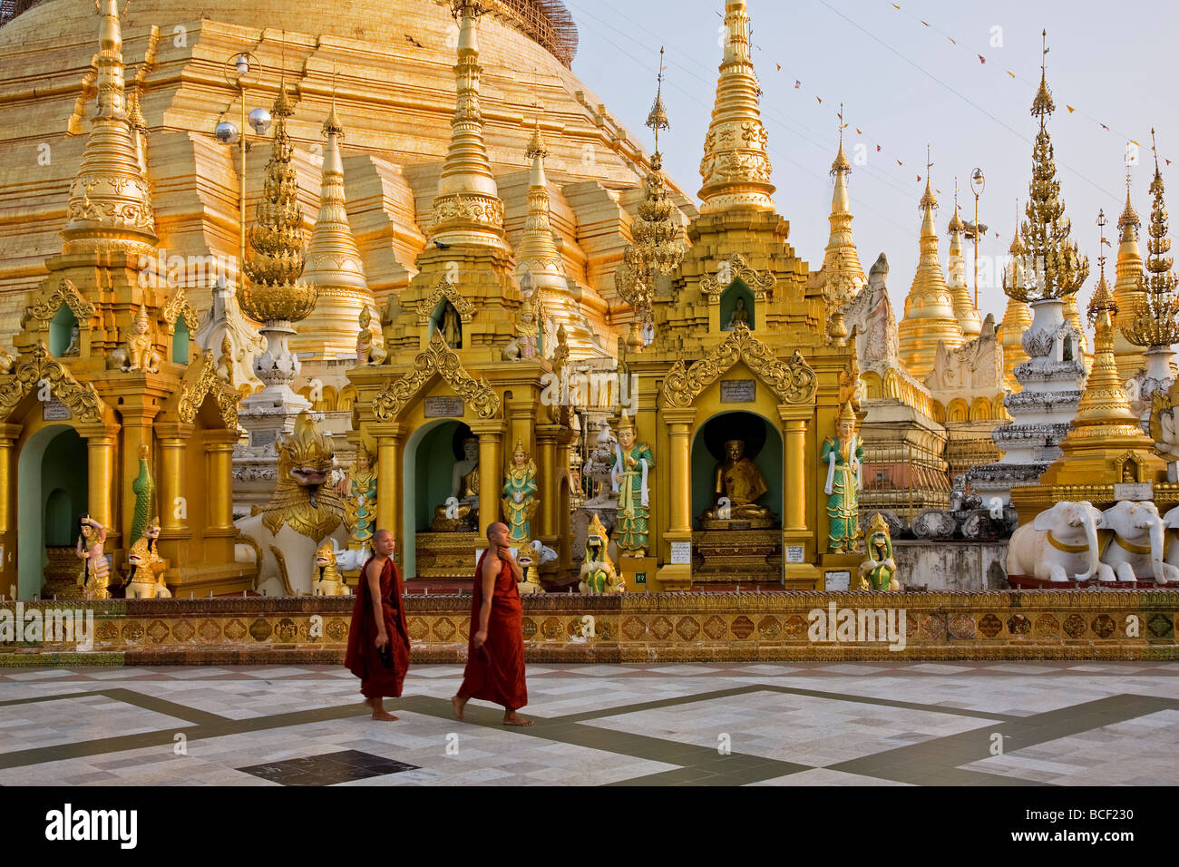 Myanmar, Burma, Yangon. Two Buddhist monks pass the small stupas ...