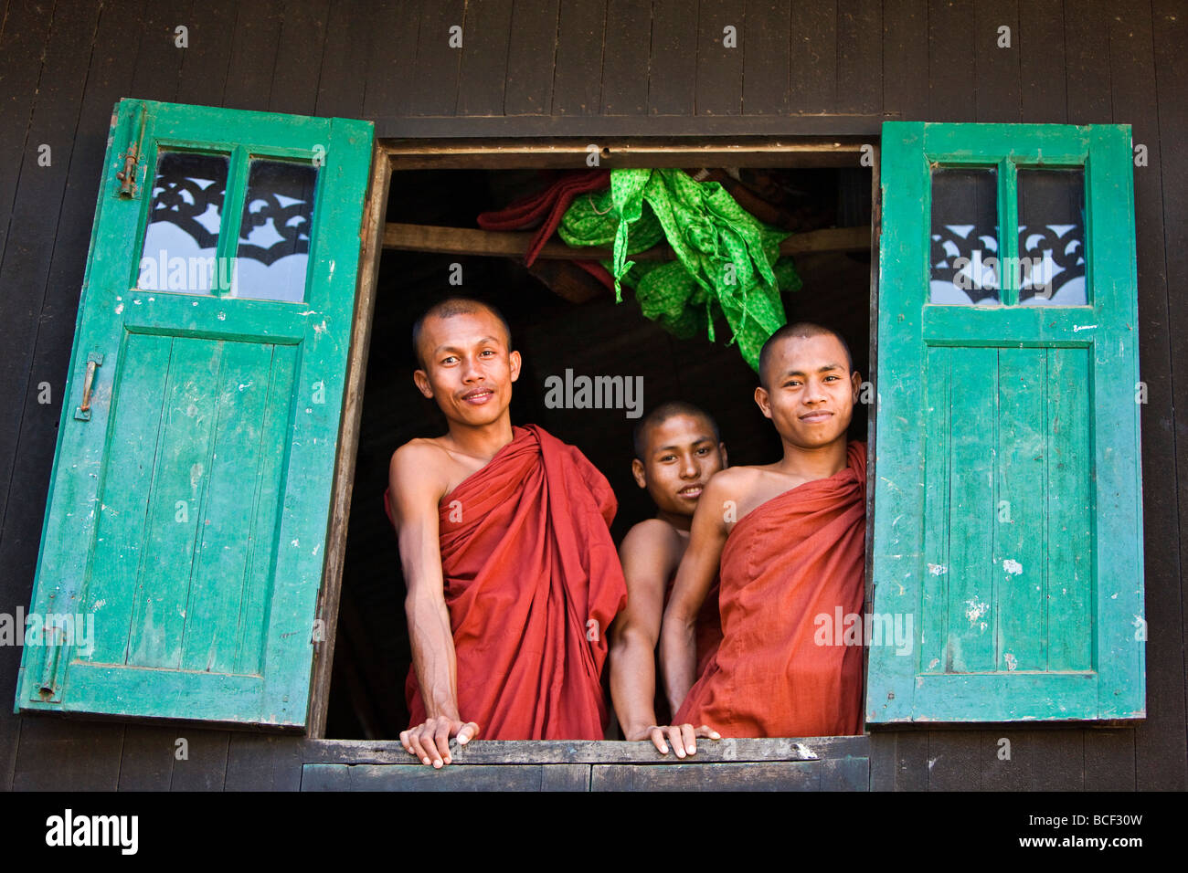 Myanmar, Burma, Rakhine State, Sittwe. Three novice monks look out of ...