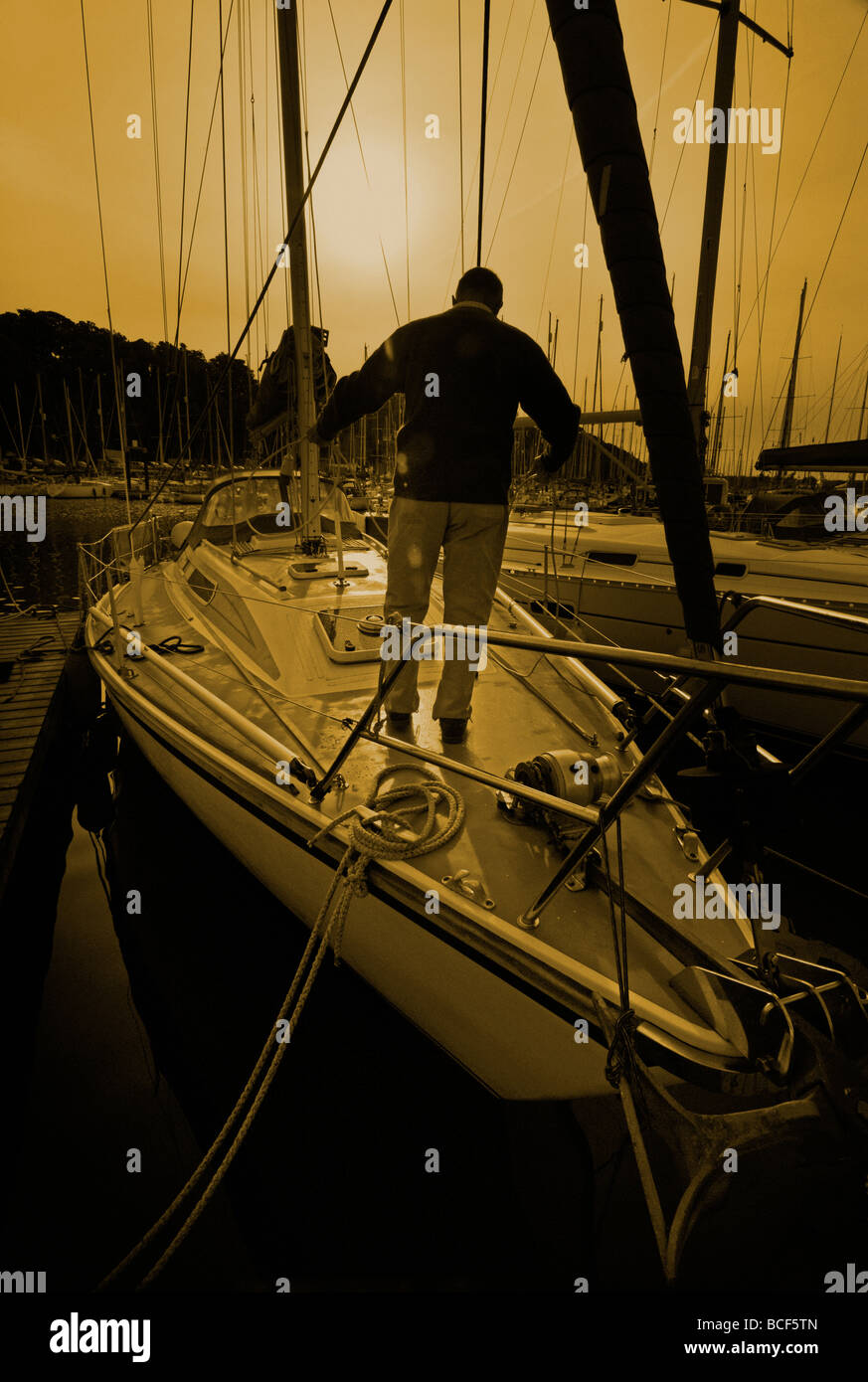 man coiling rope on sailing boat moored up as sunset Stock Photo - Alamy