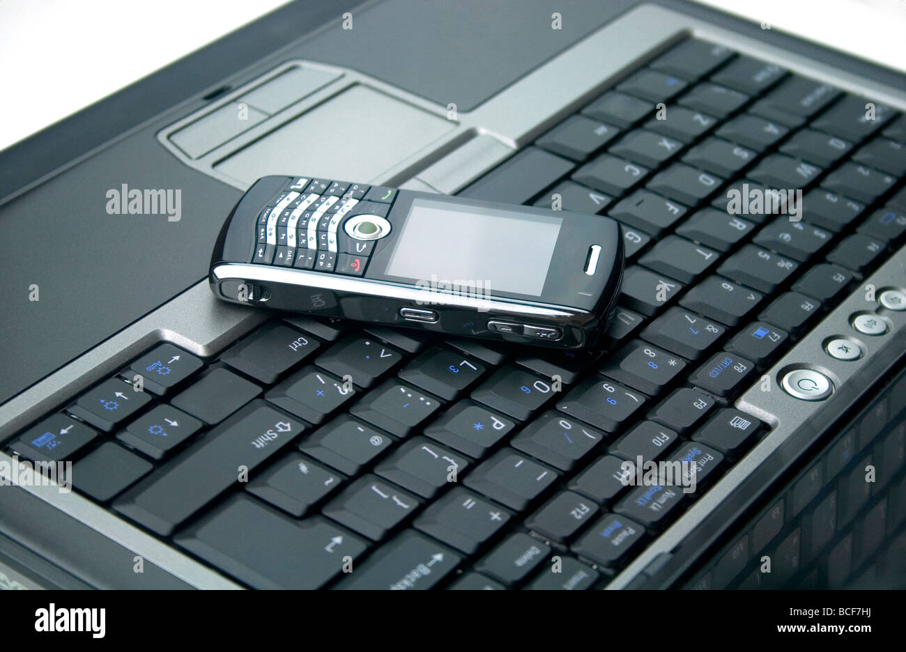 Mobile phone lying on a laptop Stock Photo - Alamy