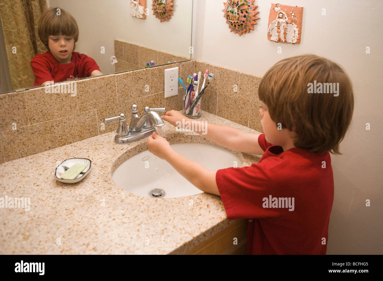a seven year old boy washing his hands with soap in the bathroom sink ...