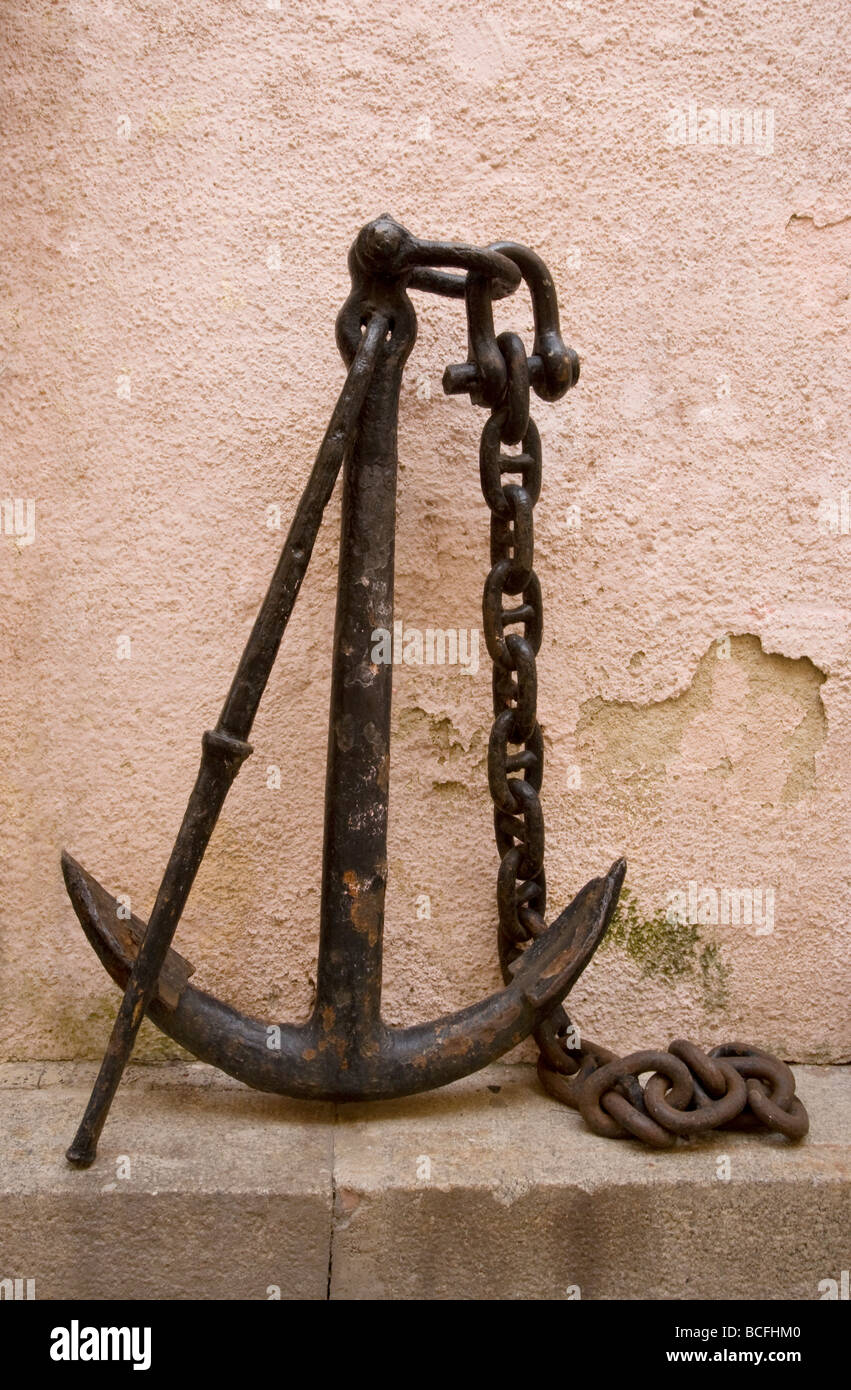 A rusty old anchor decoratively placed by a pale pink wall, Sardinia ...