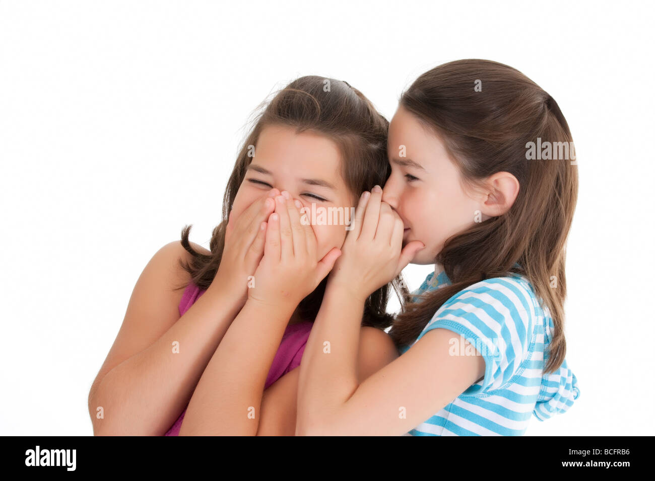 Two Caucasian girls telling secrets on white background Stock Photo - Alamy