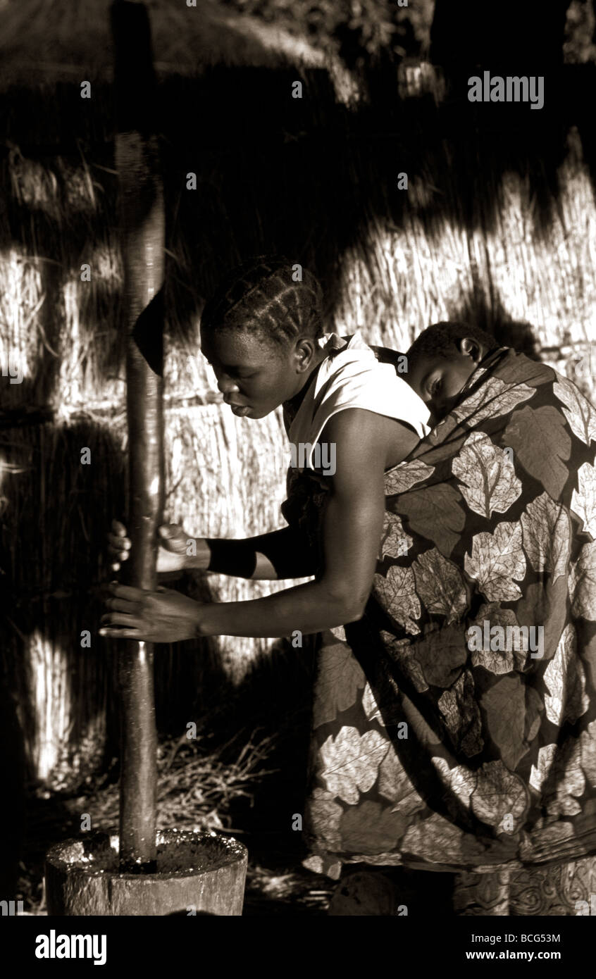woman pounding corn with mortar and pestle in village south luangwa ...