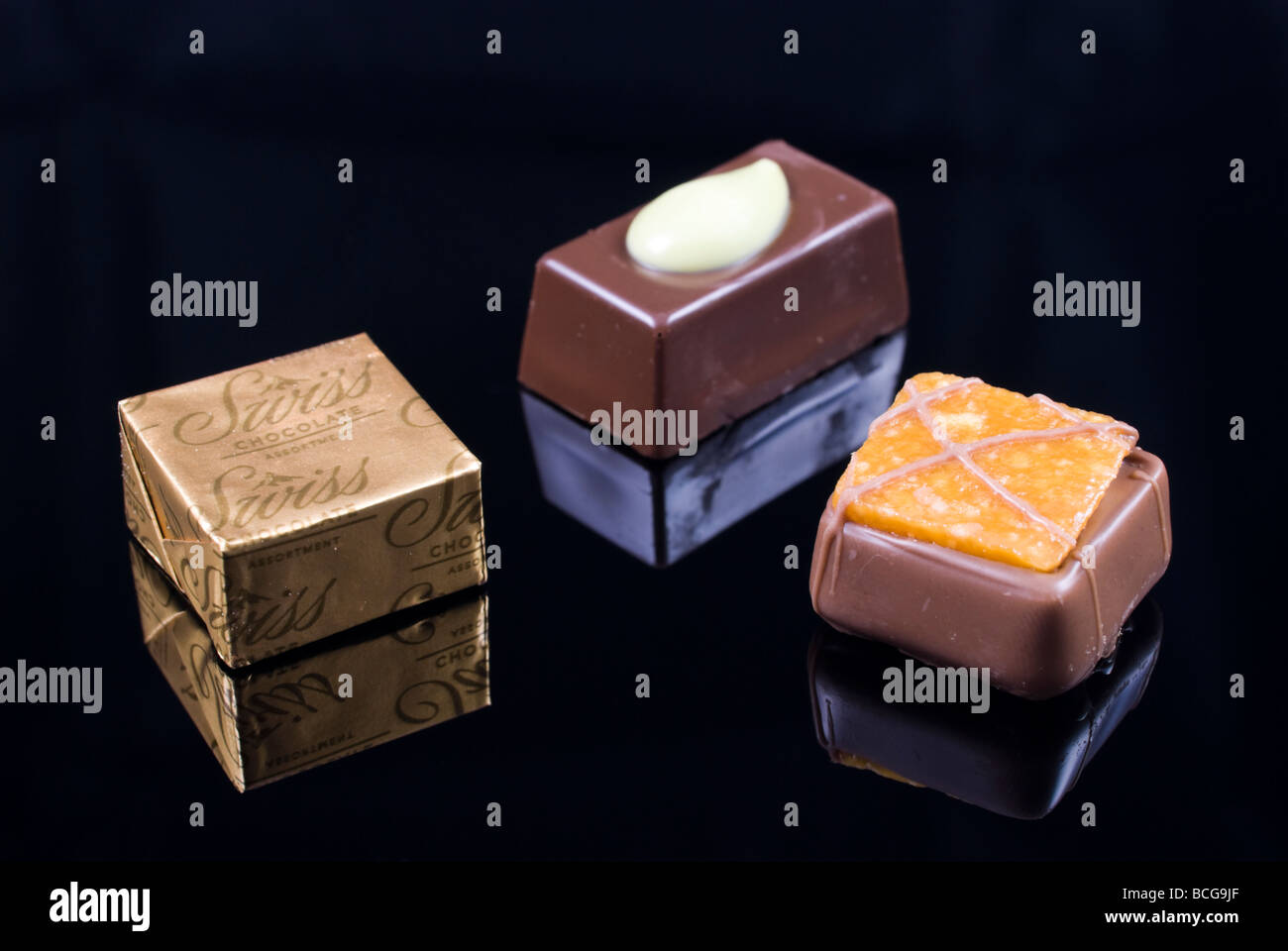 Selection of milk, dark and white chocolates arranged on dark ...