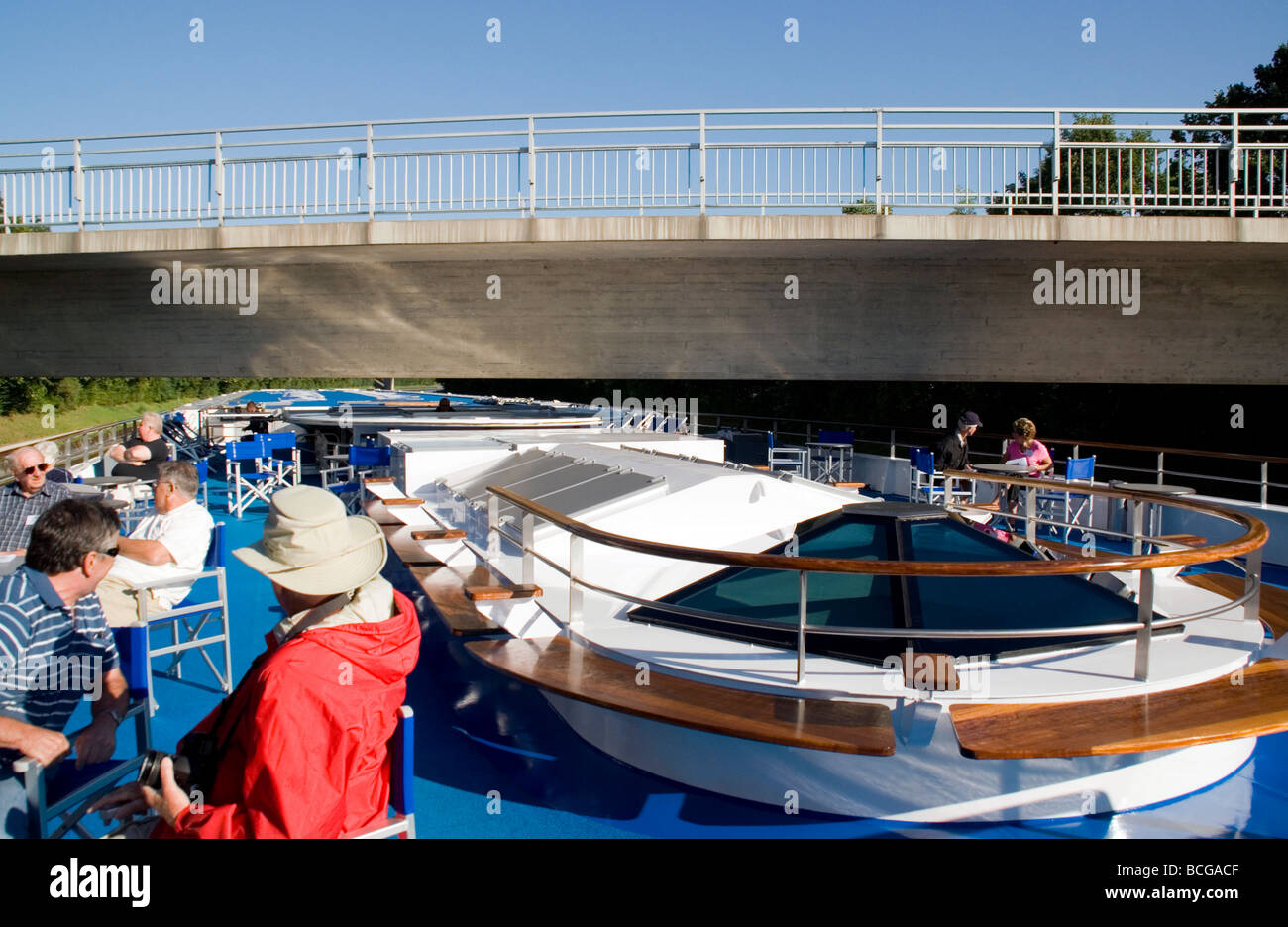 Cruise passengers on observation deck watching ship with wheel house ...