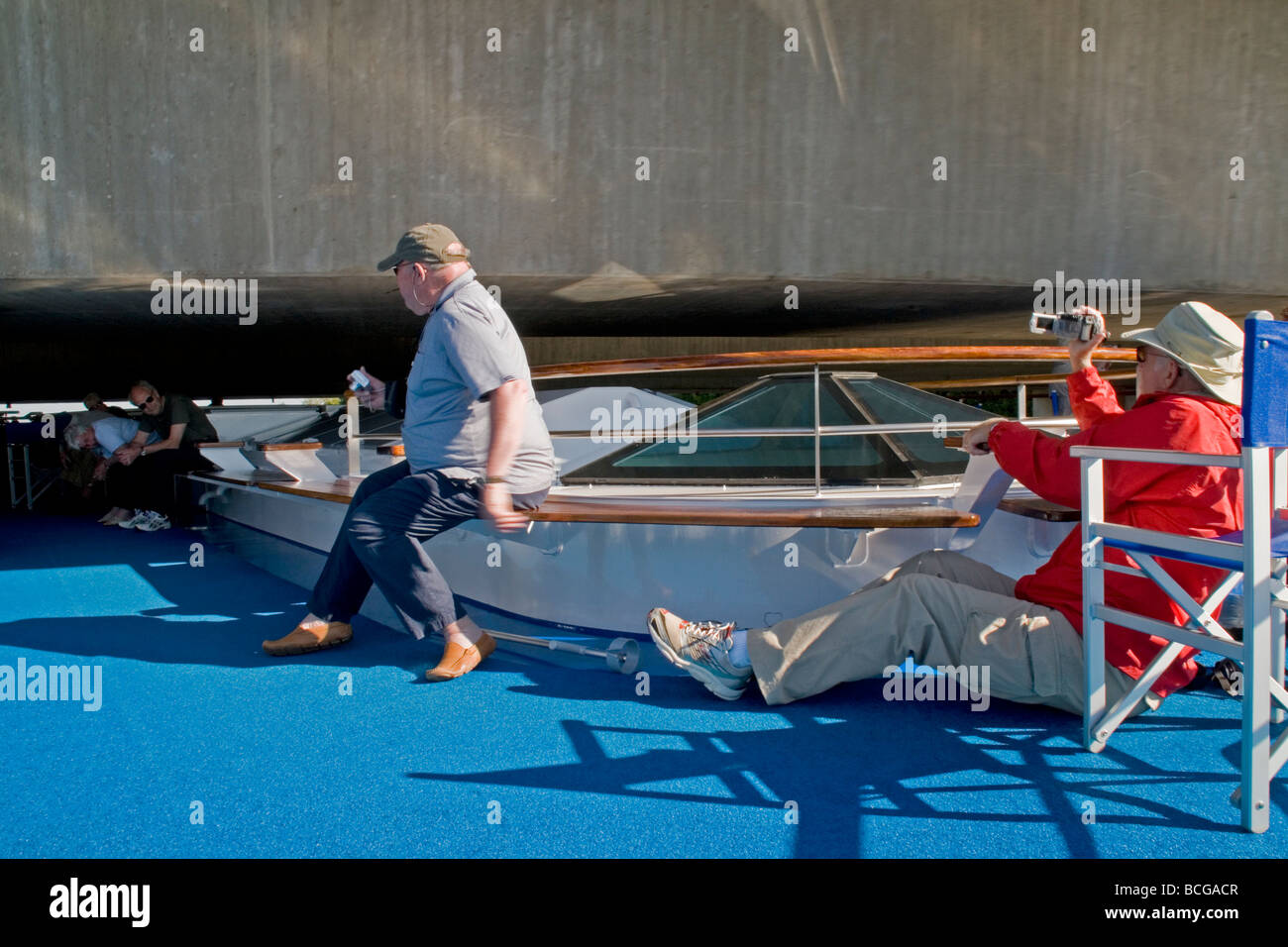 Cruise passengers on observation deck watching ship with wheel house ...