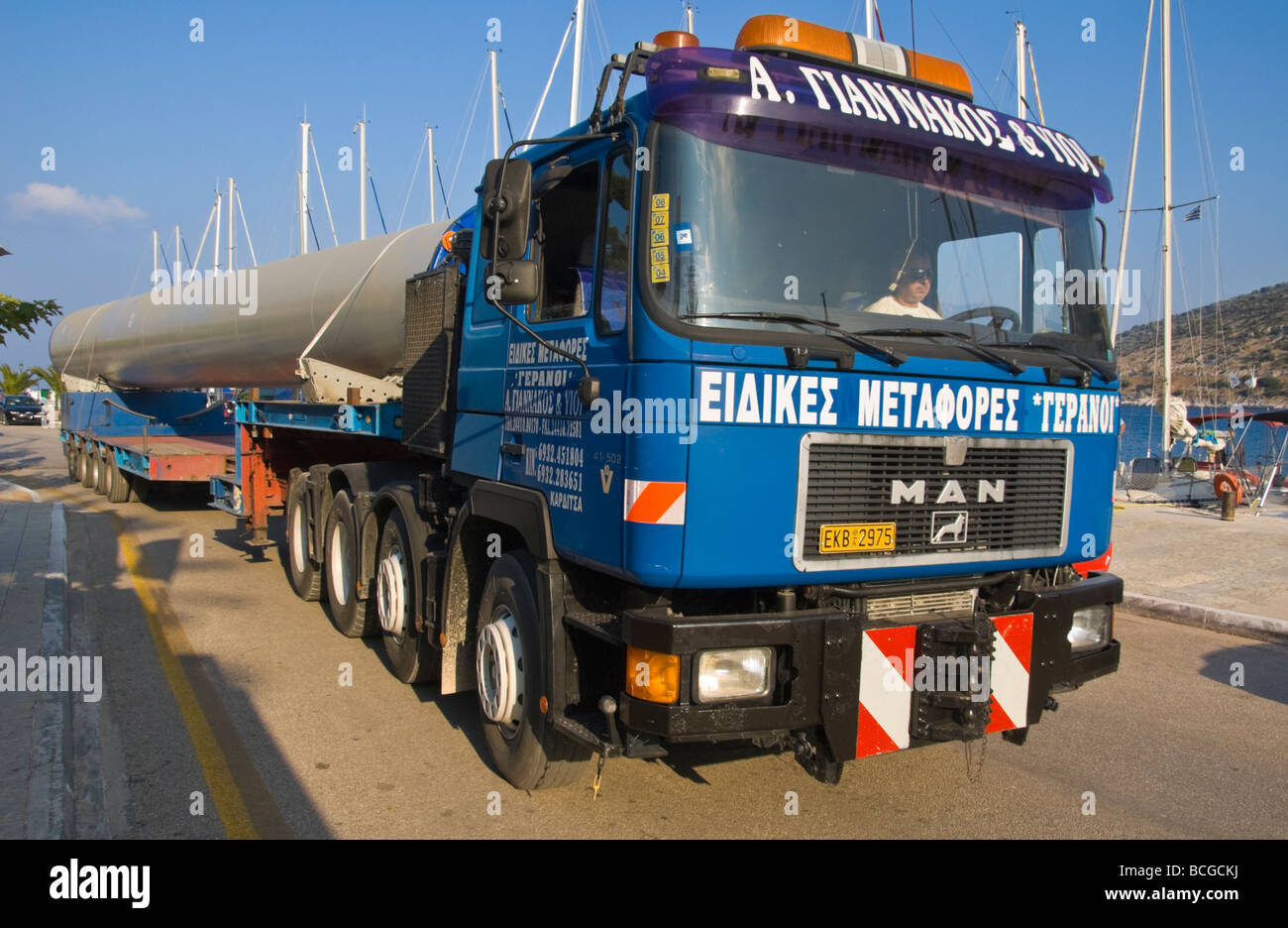 Wind turbine mast being transported on lorry by road through Agia ...