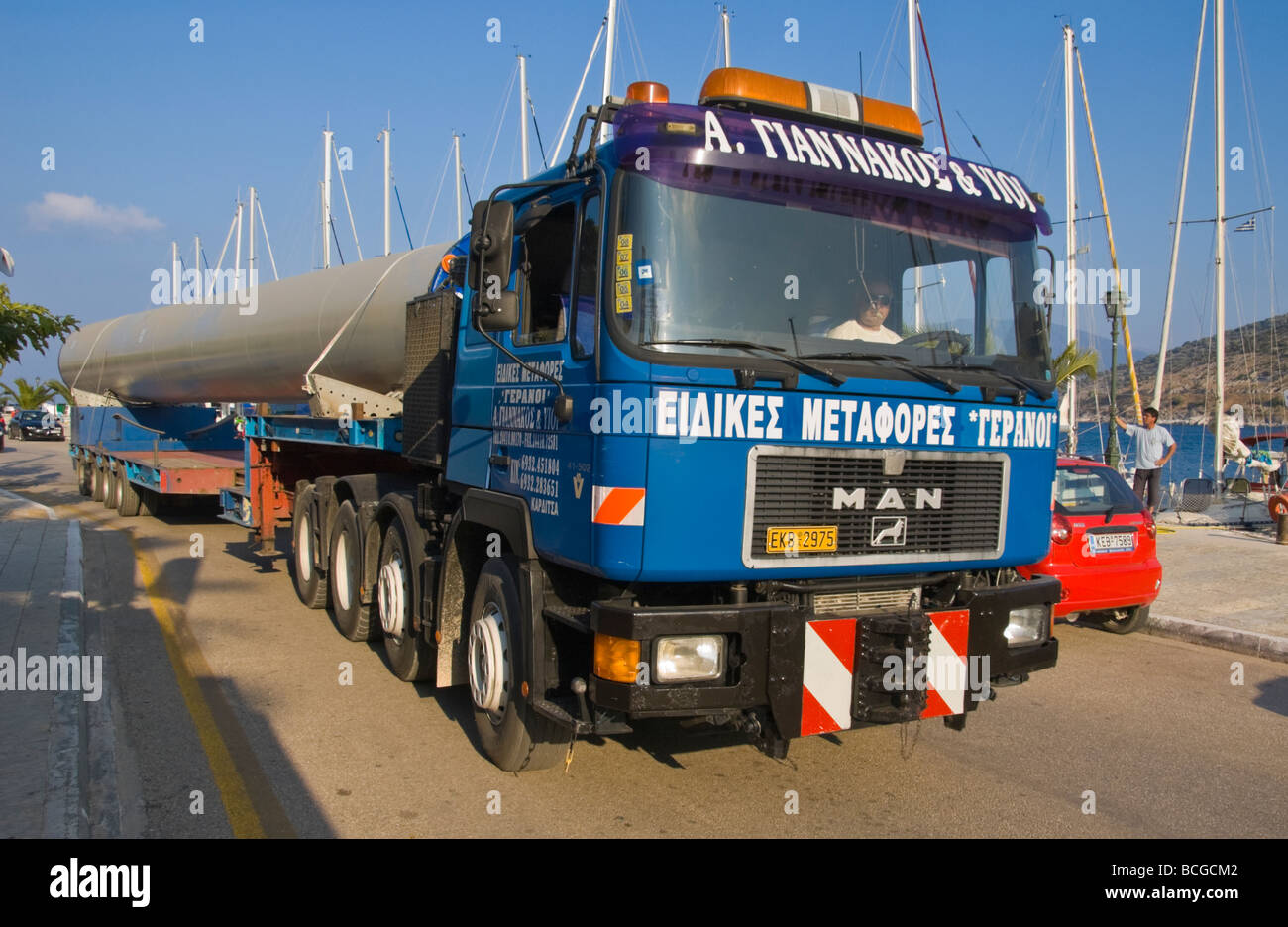 Wind turbine mast being transported on lorry by road through Agia ...