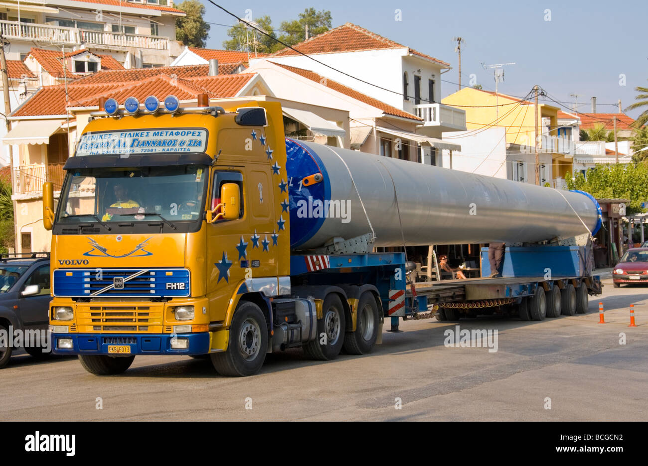 Wind turbine mast being transported on lorry by road through Agia ...