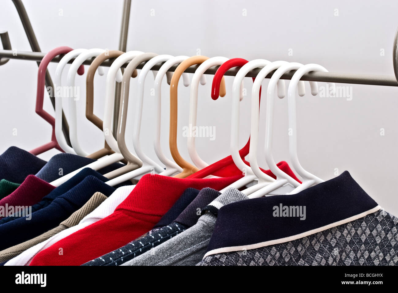 Shirts on hangers on a metal rack, with one red shirt out of place ...