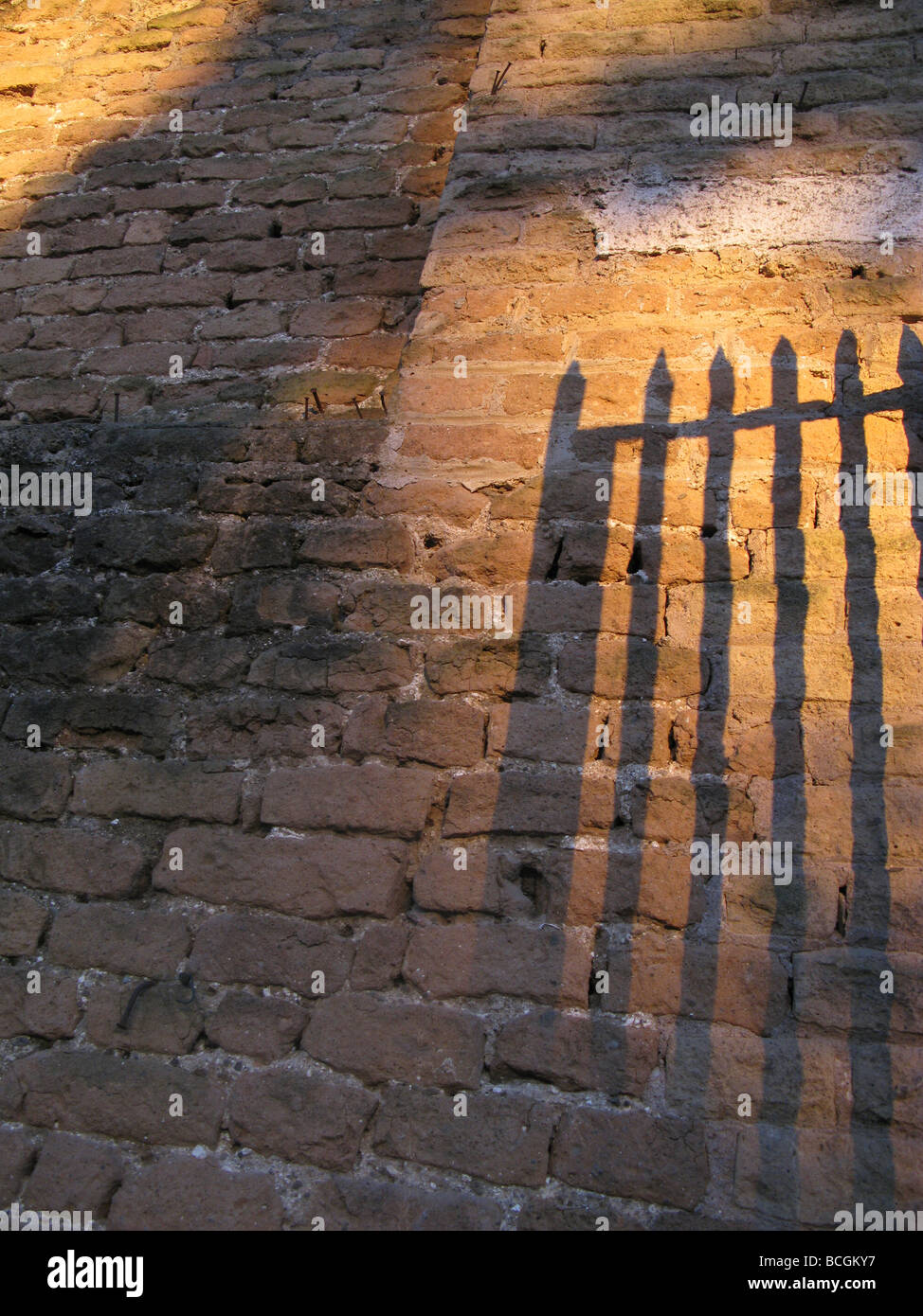 metal fence shadow on orange brick wall Stock Photo - Alamy