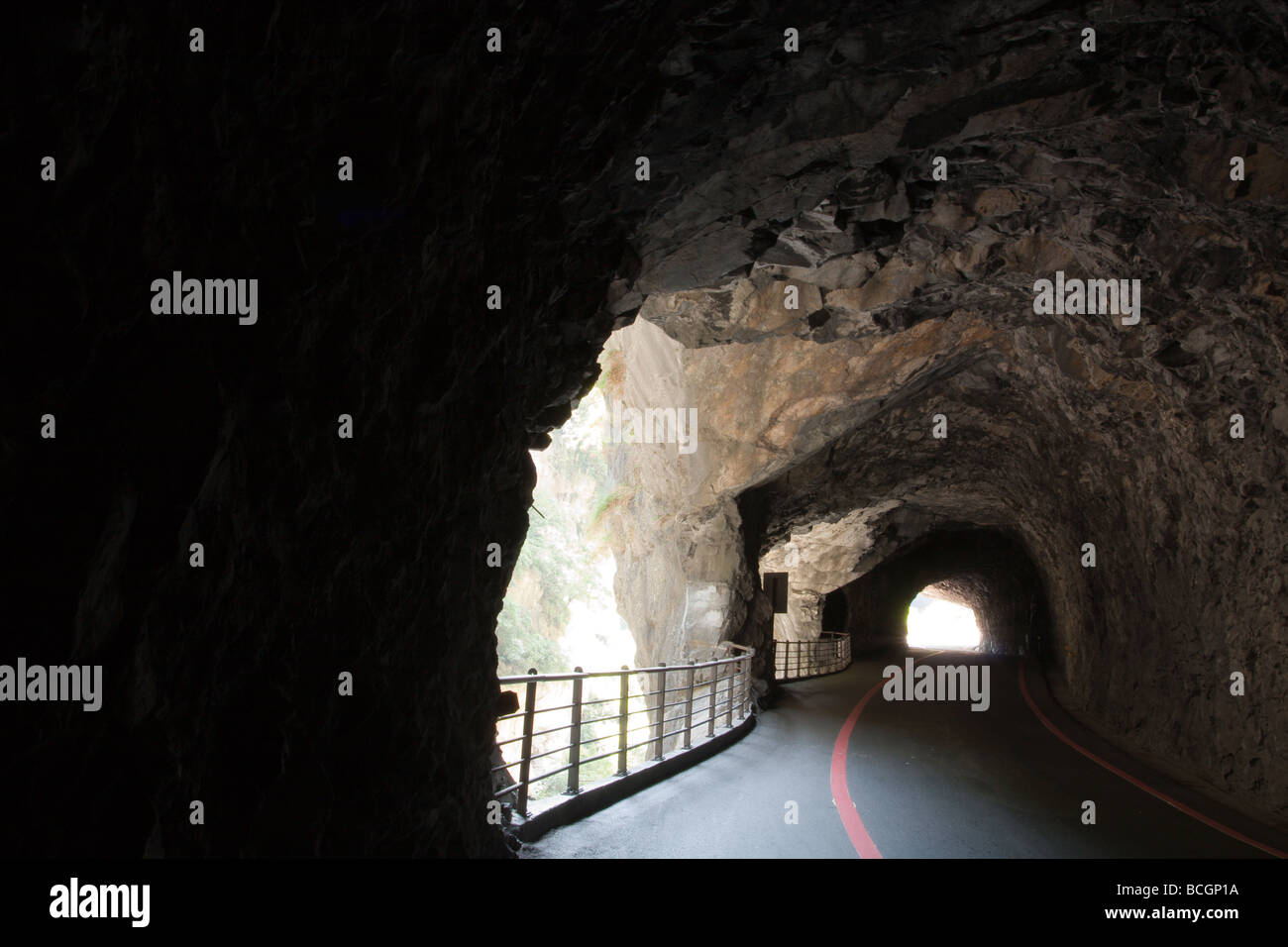 Cliffside tunnel's galleries, road under rock overhang along marble ...