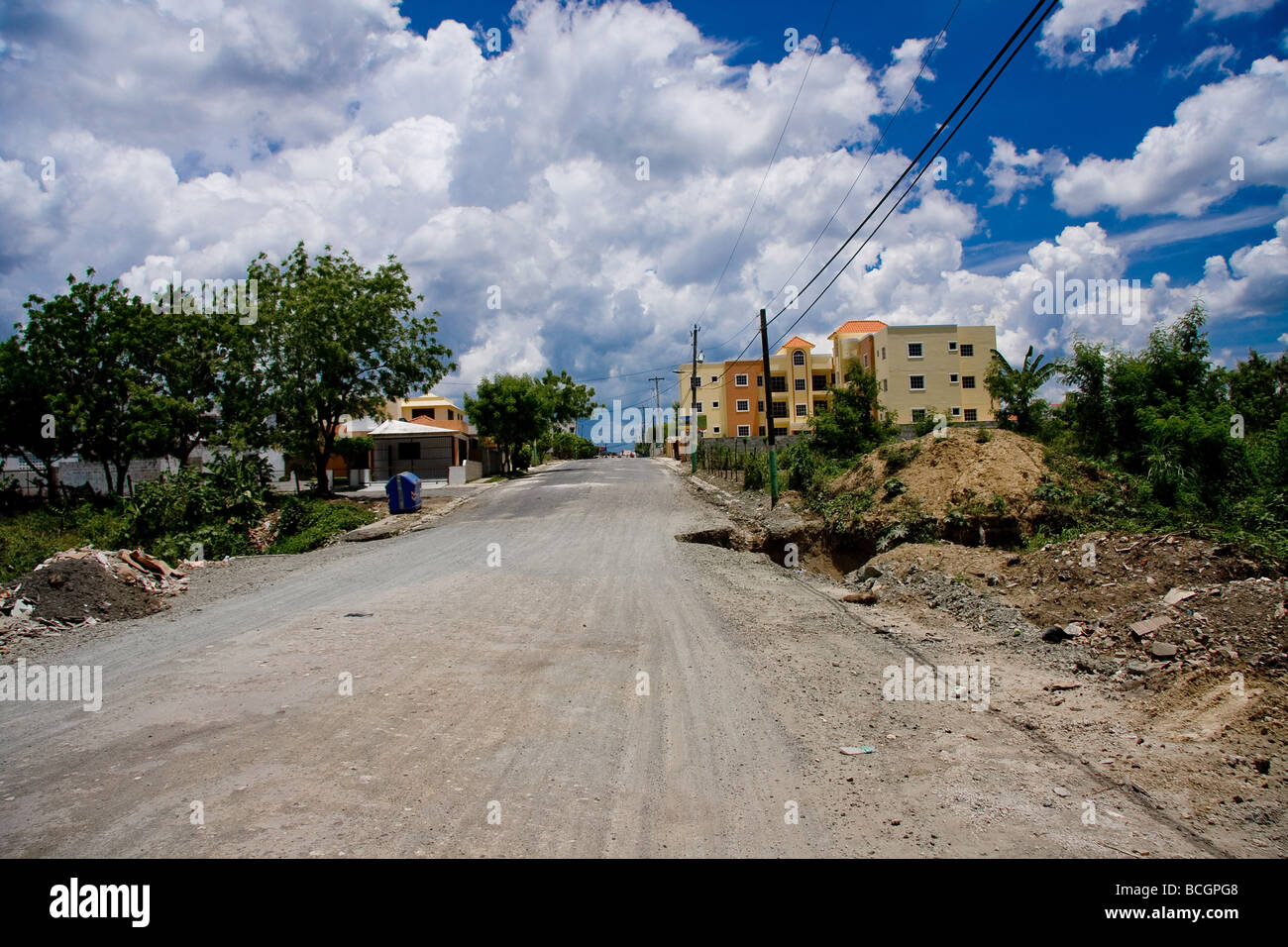 A long straight road with a large dug out hole by the side of the road ...
