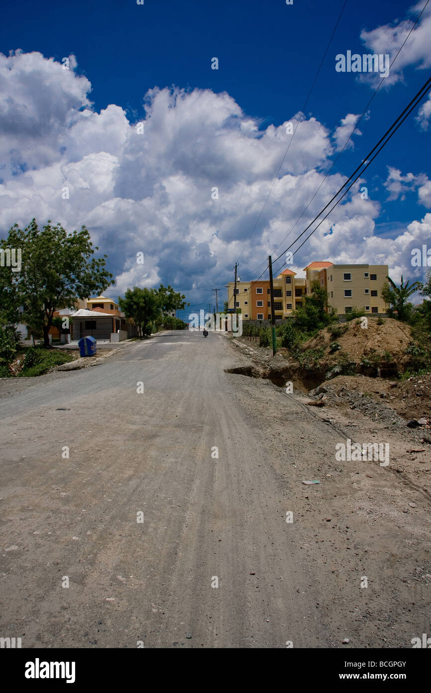 A long straight road with a large dug out hole by the side of the road ...