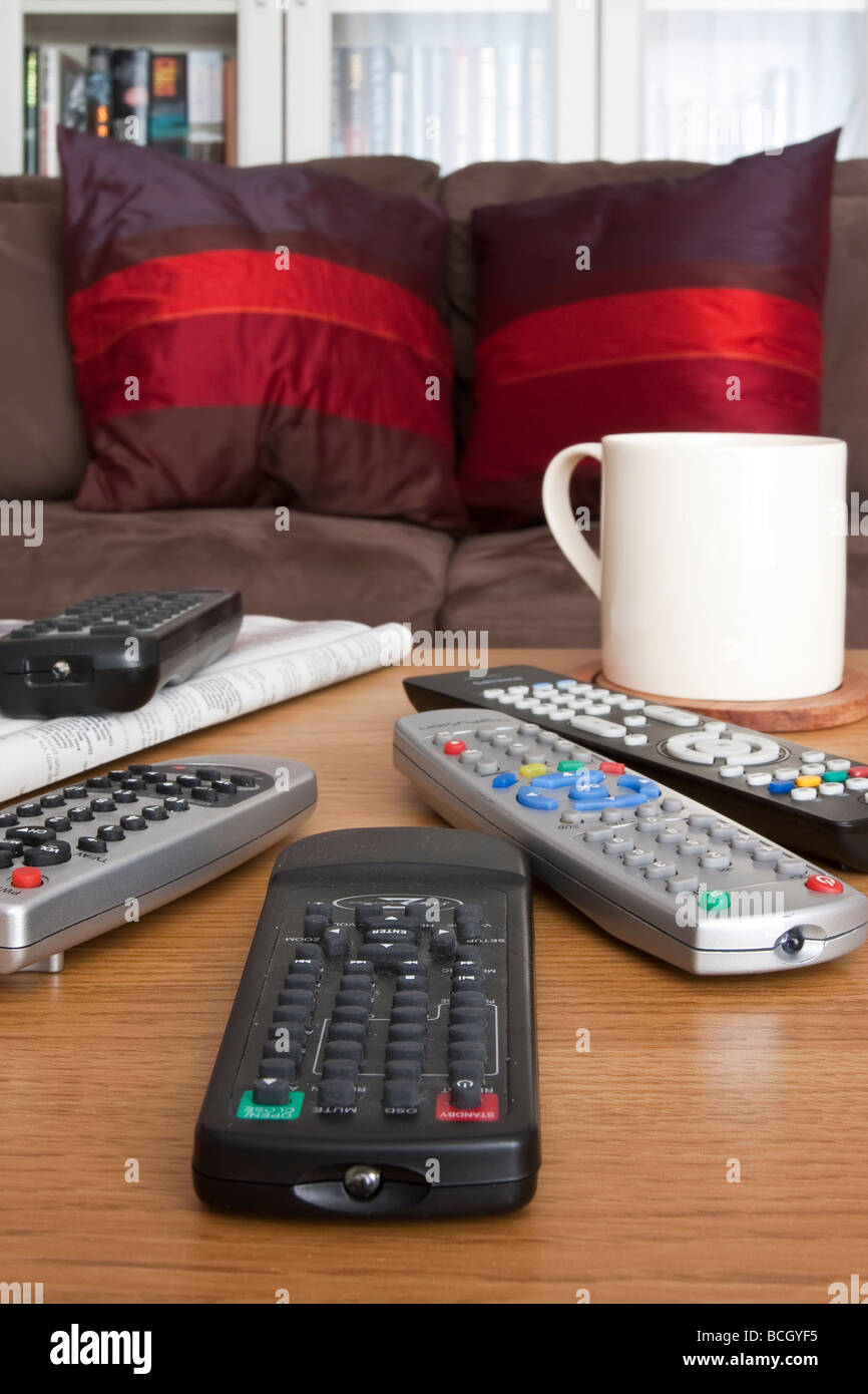 A coffee table with a selection of tv remotes a mug and television ...