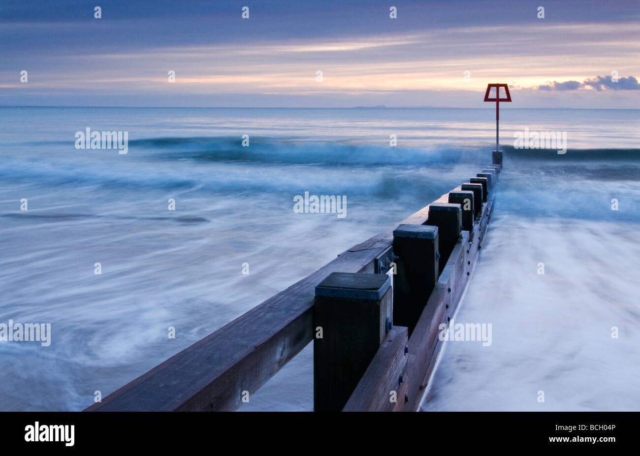 Dawn breaking over wooden groyne at Swanage on the Dorset Purbeck coast ...