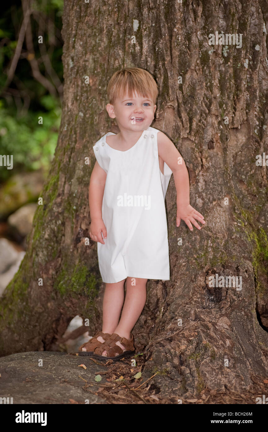 little boy standing by a tree outside posing and smiling Stock Photo ...