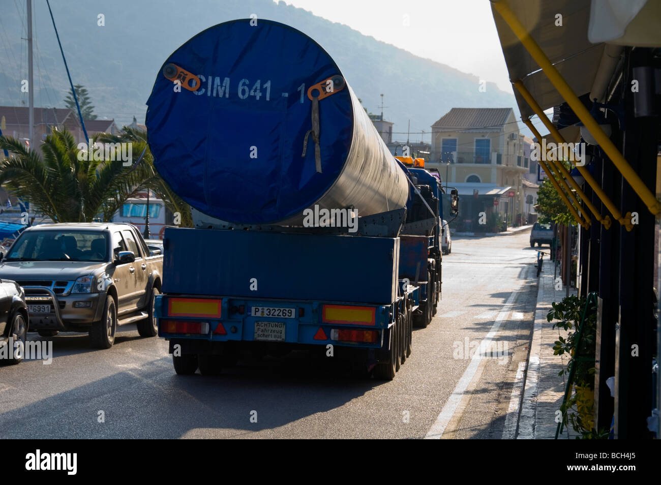 Wind turbine mast being transported on lorry by road through Agia ...