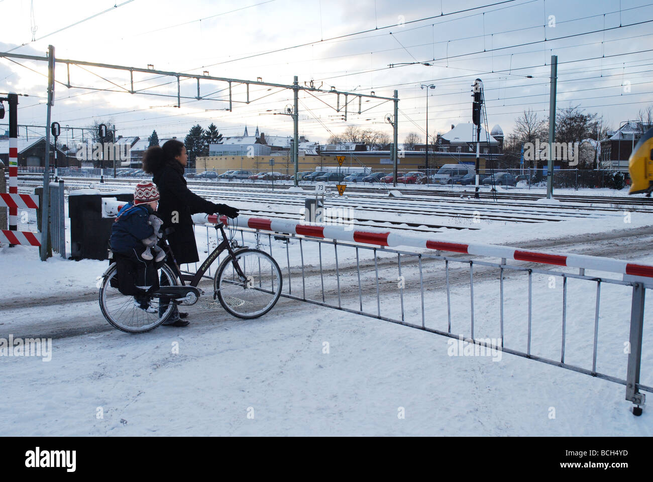 cyclist waiting at railway crossing in winter Stock Photo - Alamy