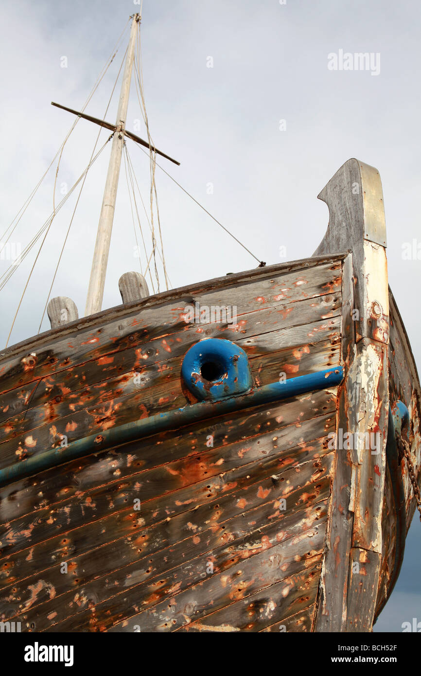 The paint stripped remains of a large wooden ship rot against a cloudy ...