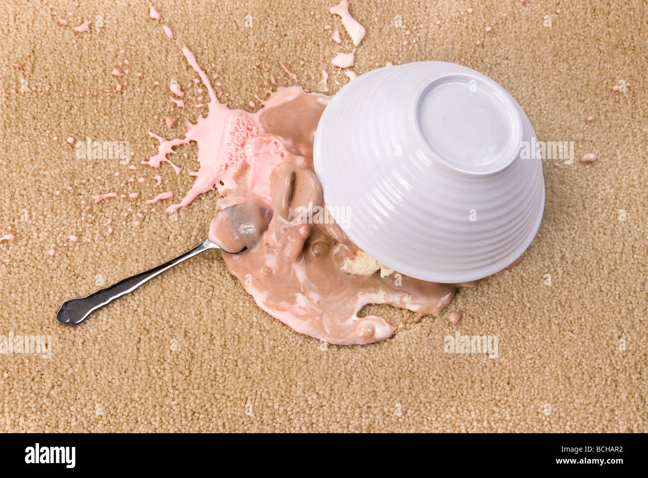 A bowl of spilled Neopolitan ice cream on white carpet that is melting ...