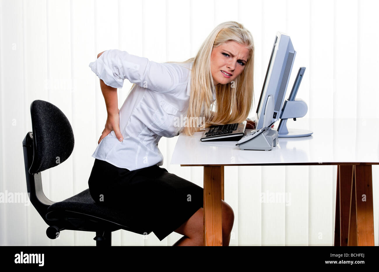 young woman with aching back in office Stock Photo - Alamy