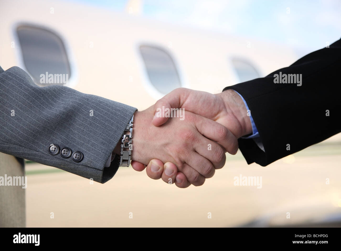 Businessmen shake hands in front of jet Stock Photo - Alamy