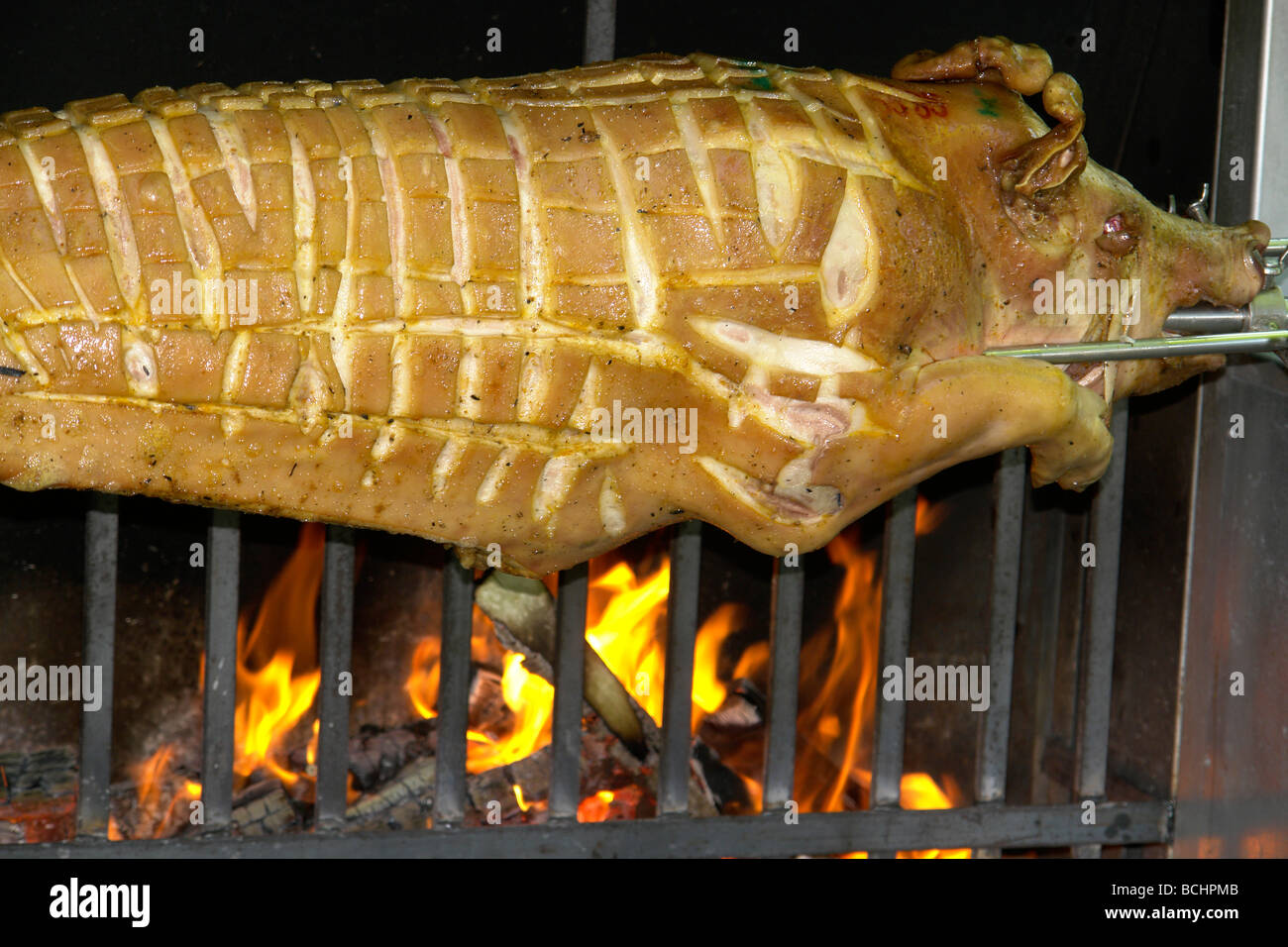Open fire BBQ pig turning in front of tourists Bavaria beer garden ...