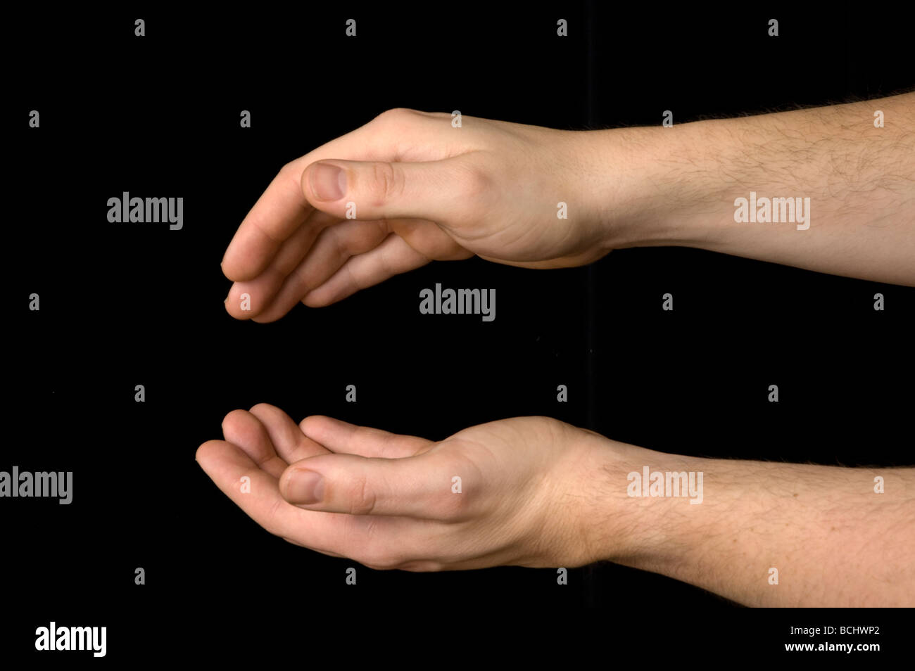 male hands enclosing and encompassing and cupping against black Stock ...