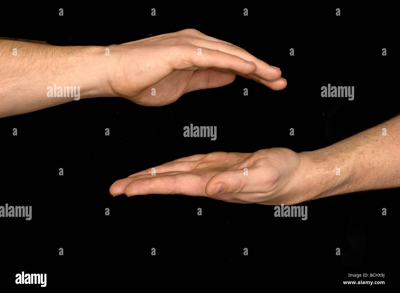 male hands enclosing and encompassing and cupping against black Stock ...