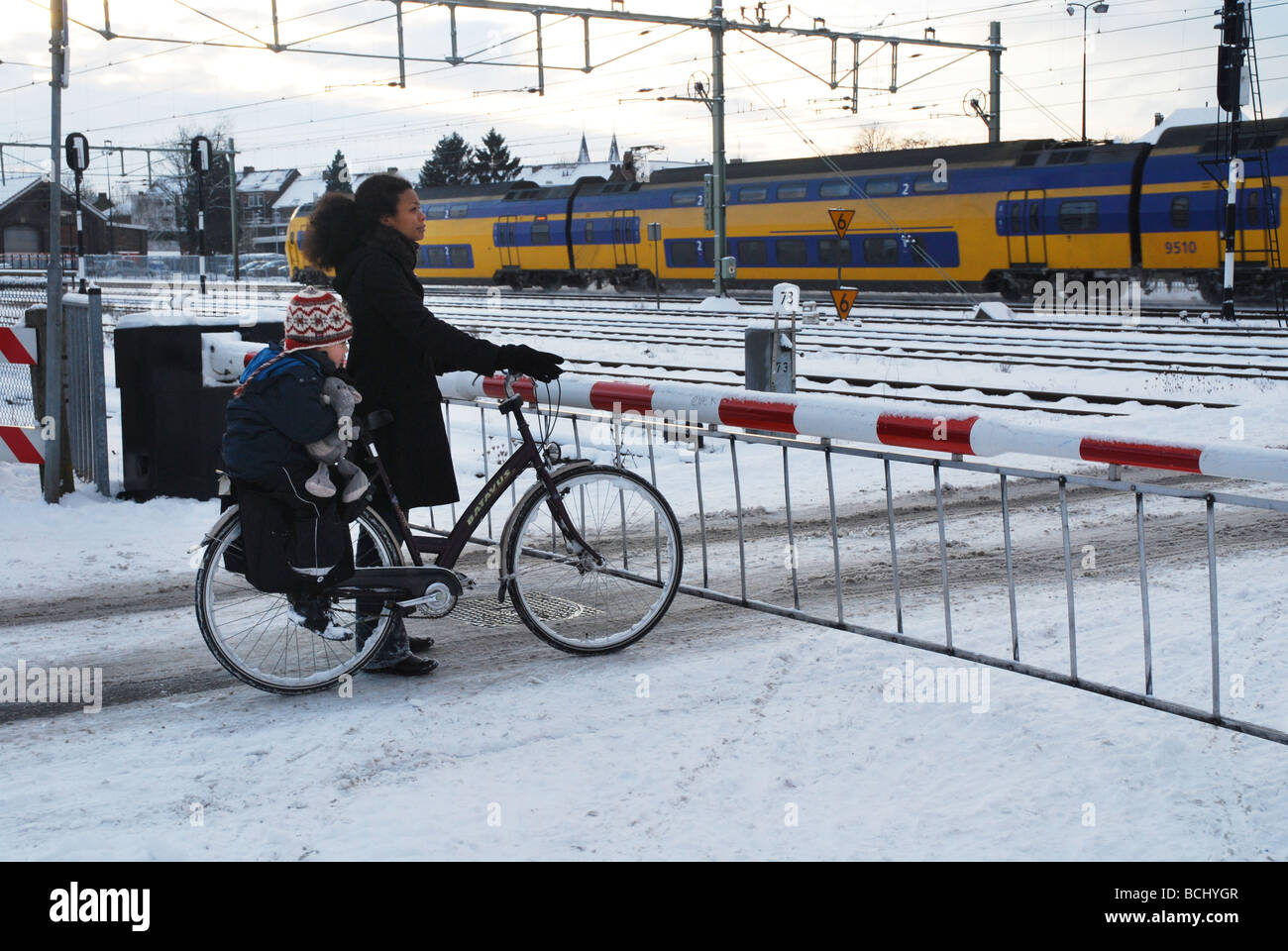 cyclist waiting at railway crossing in winter Stock Photo - Alamy
